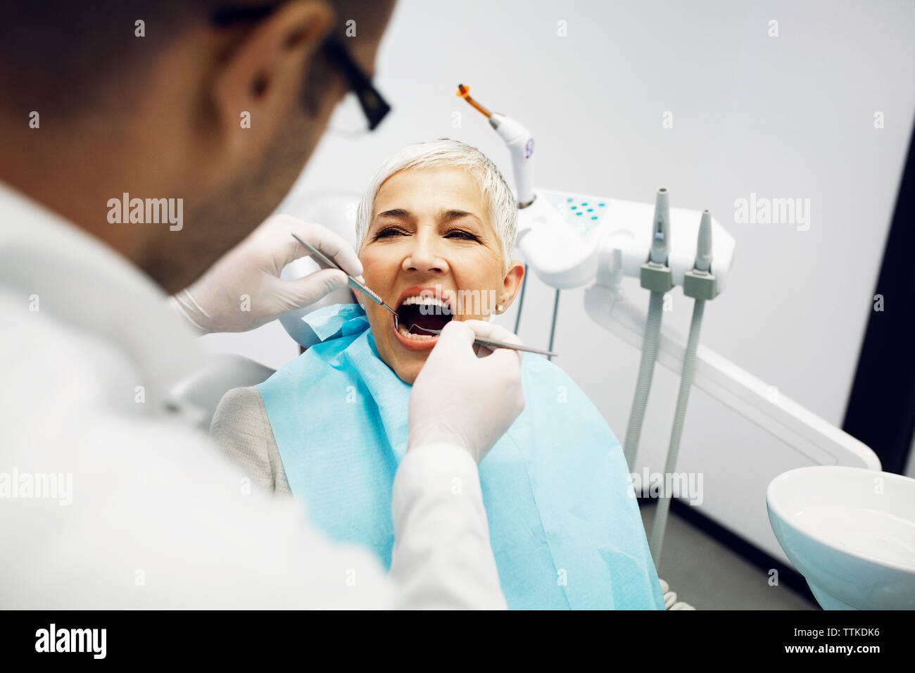 Male dentist examining patient's teeth at clinic Stock Photo - Alamy