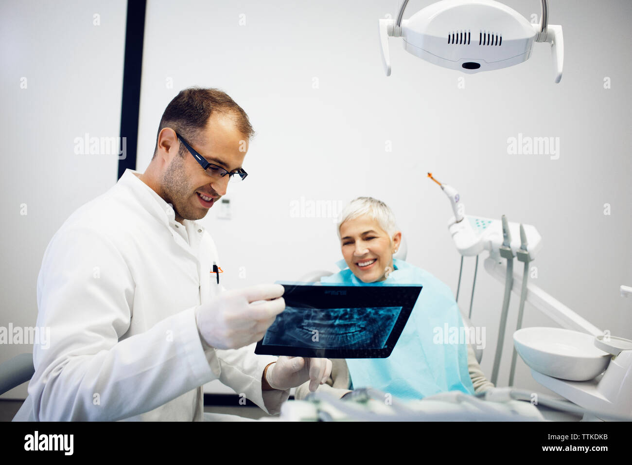 Dentist explaining x-ray to smiling patient at clinic Stock Photo - Alamy