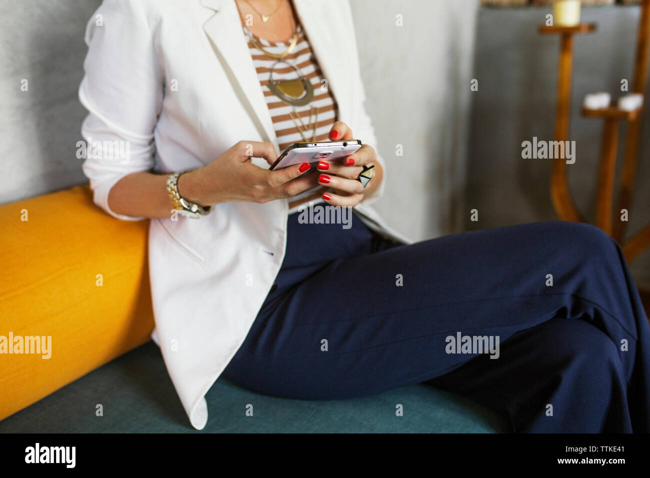 Midsection of creative businesswoman using smart phone in hotel lobby ...