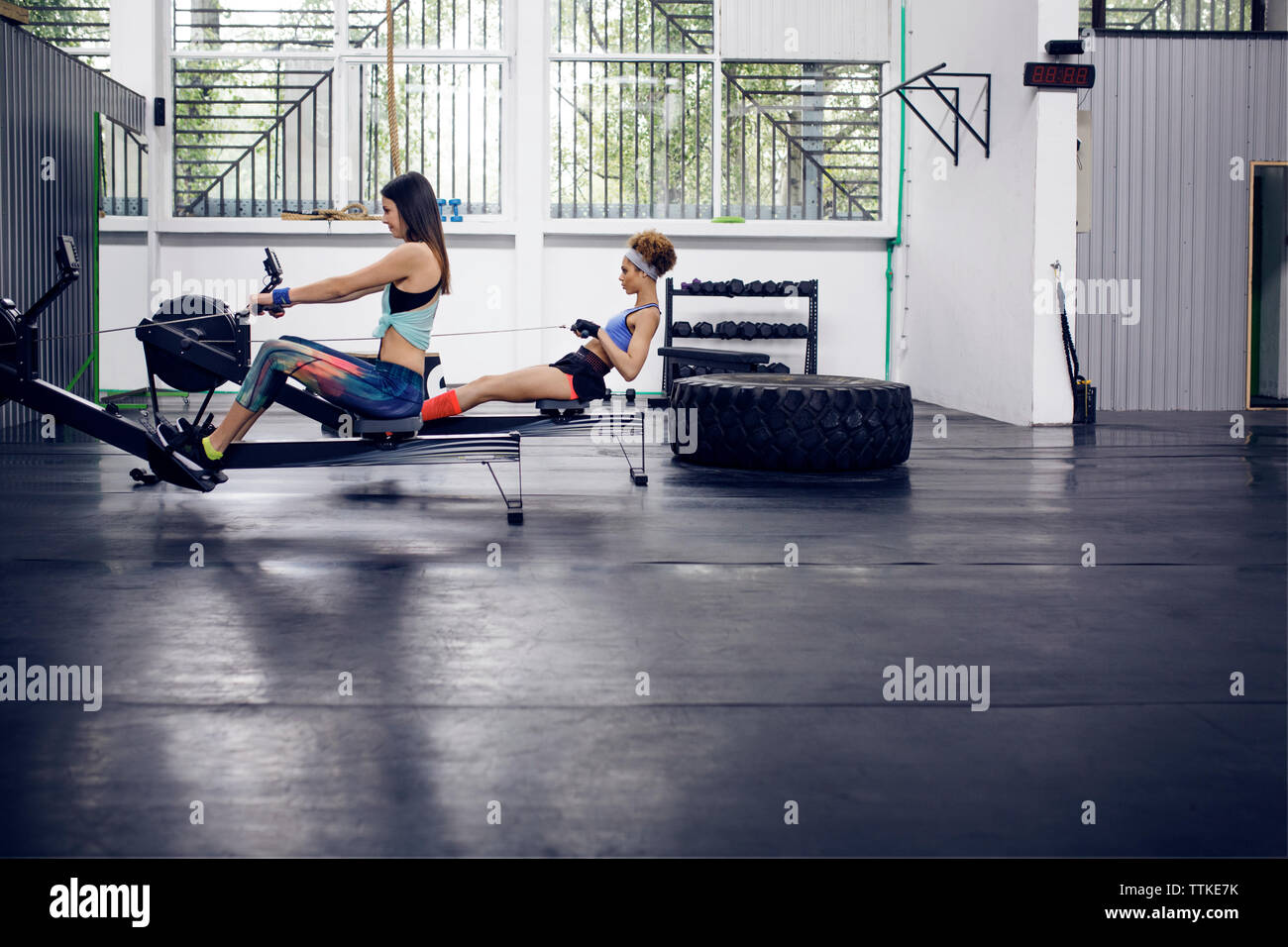 Side view of female athletes exercising on rowing machine at gym Stock ...