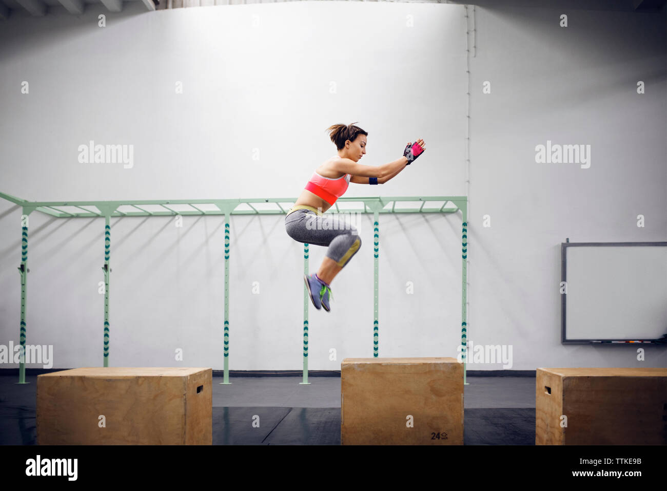Side view of confident female athlete doing box jumping at gym Stock ...
