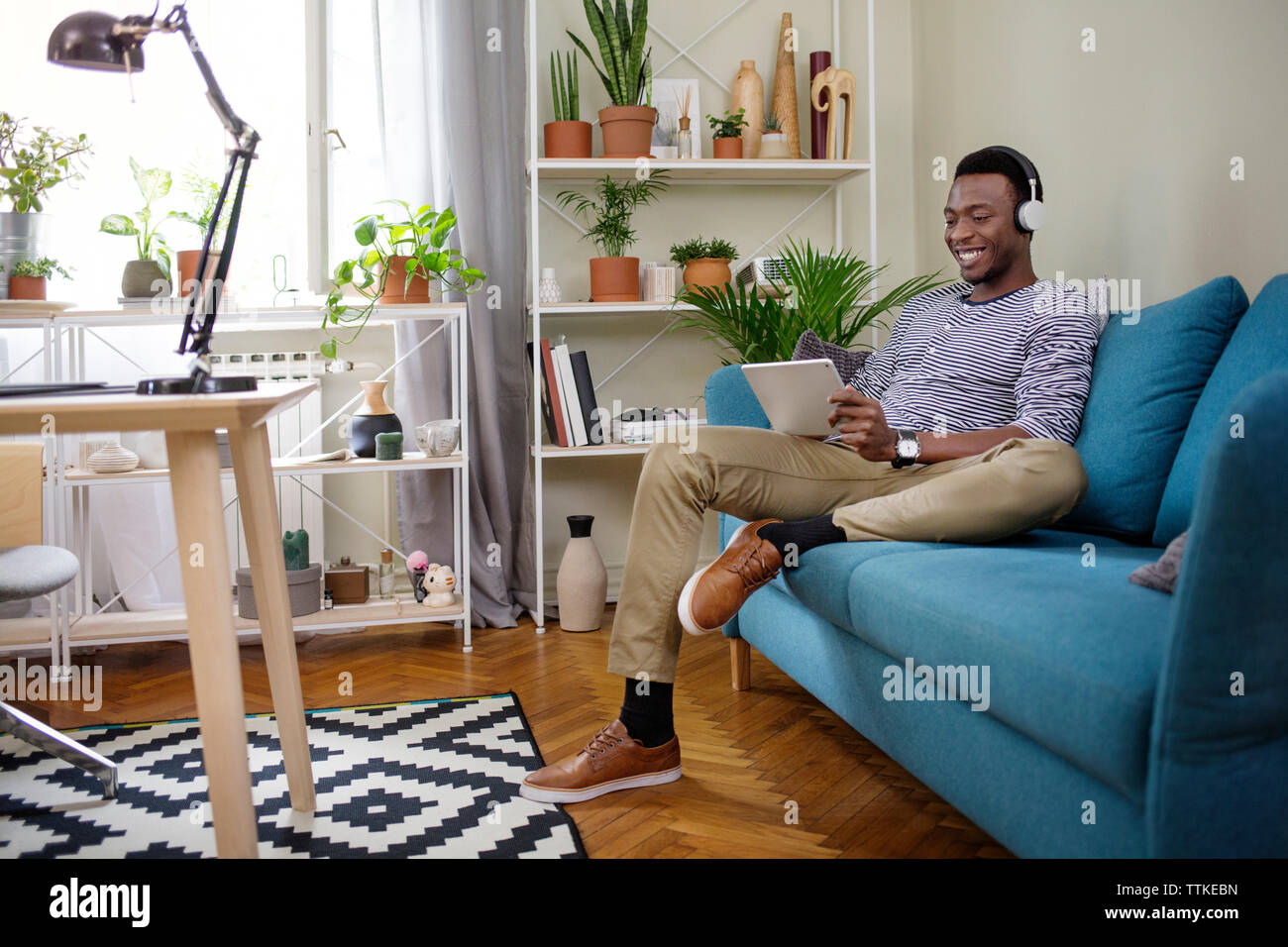 Happy man using tablet computer while sitting on sofa at home Stock ...