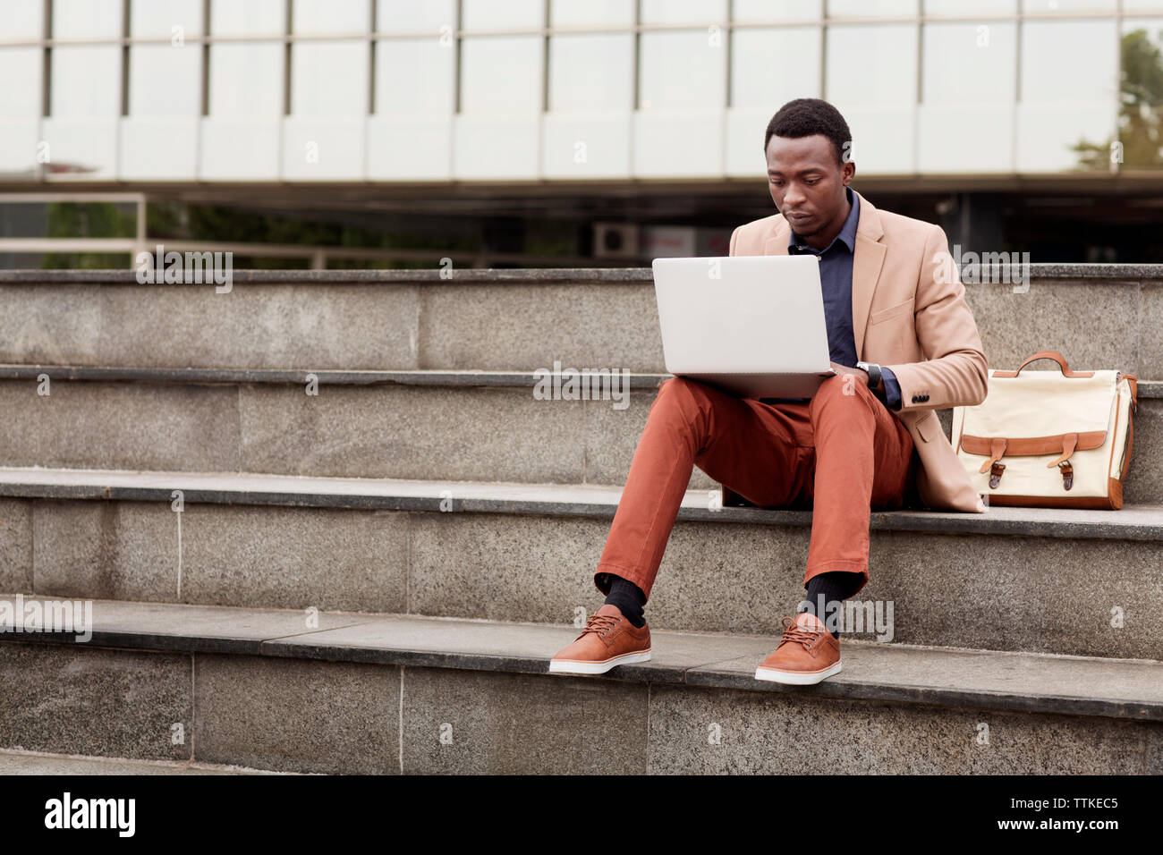 businessman using laptop while sitting on steps Stock Photo - Alamy