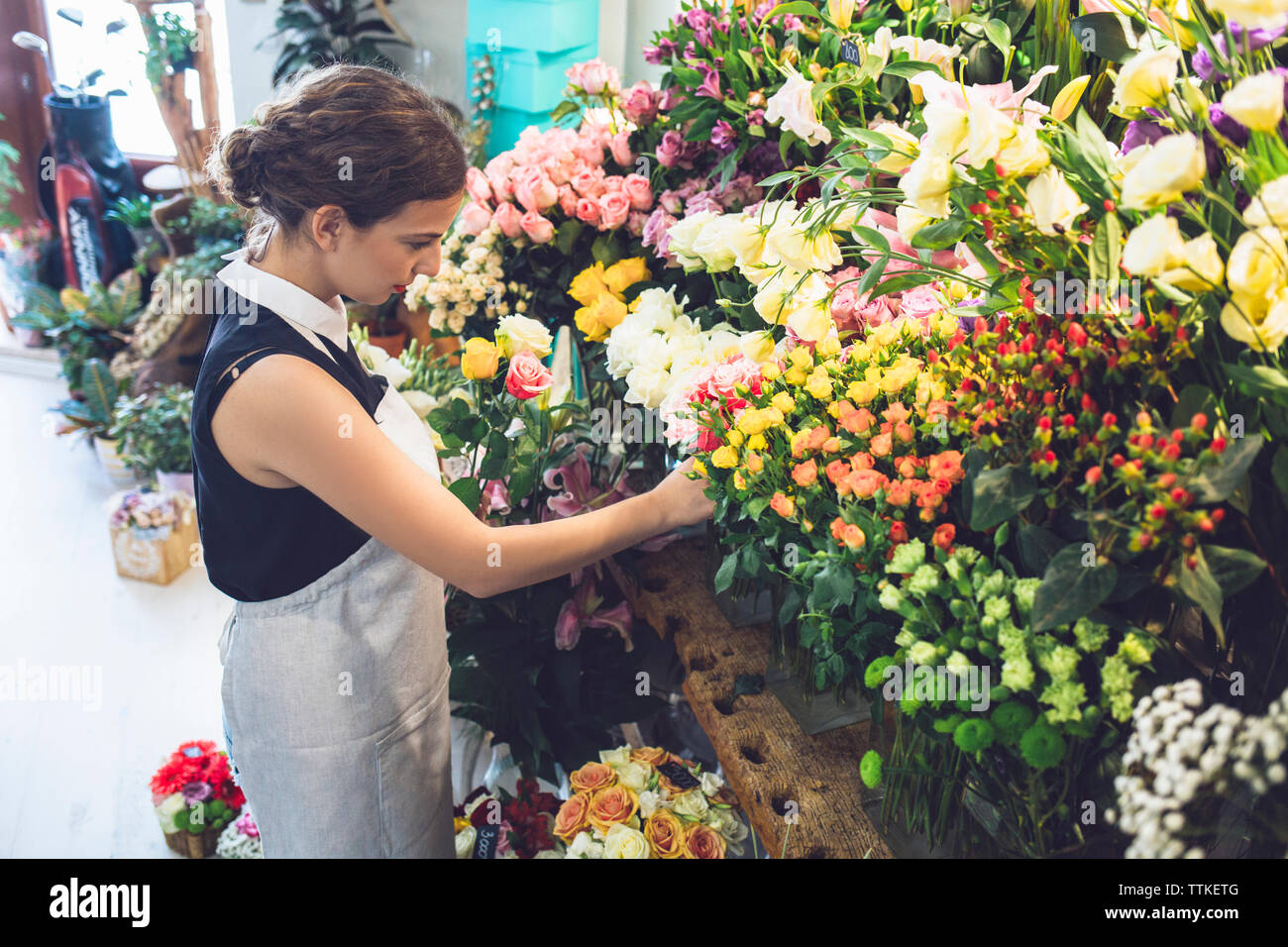 Side view of female owner arranging roses at shop Stock Photo - Alamy