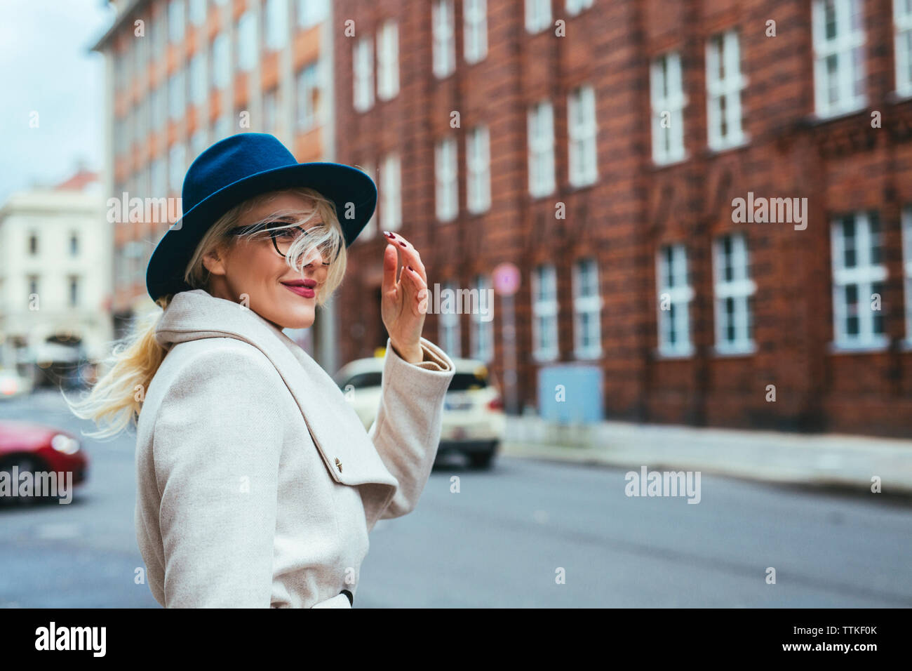 Happy woman looking away while standing on city street Stock Photo - Alamy