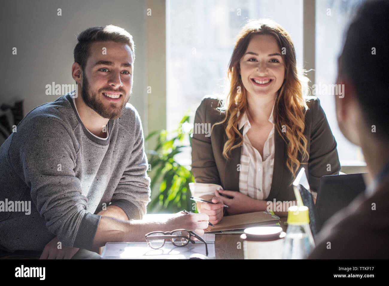 Smiling friends sitting at table in classroom Stock Photo - Alamy
