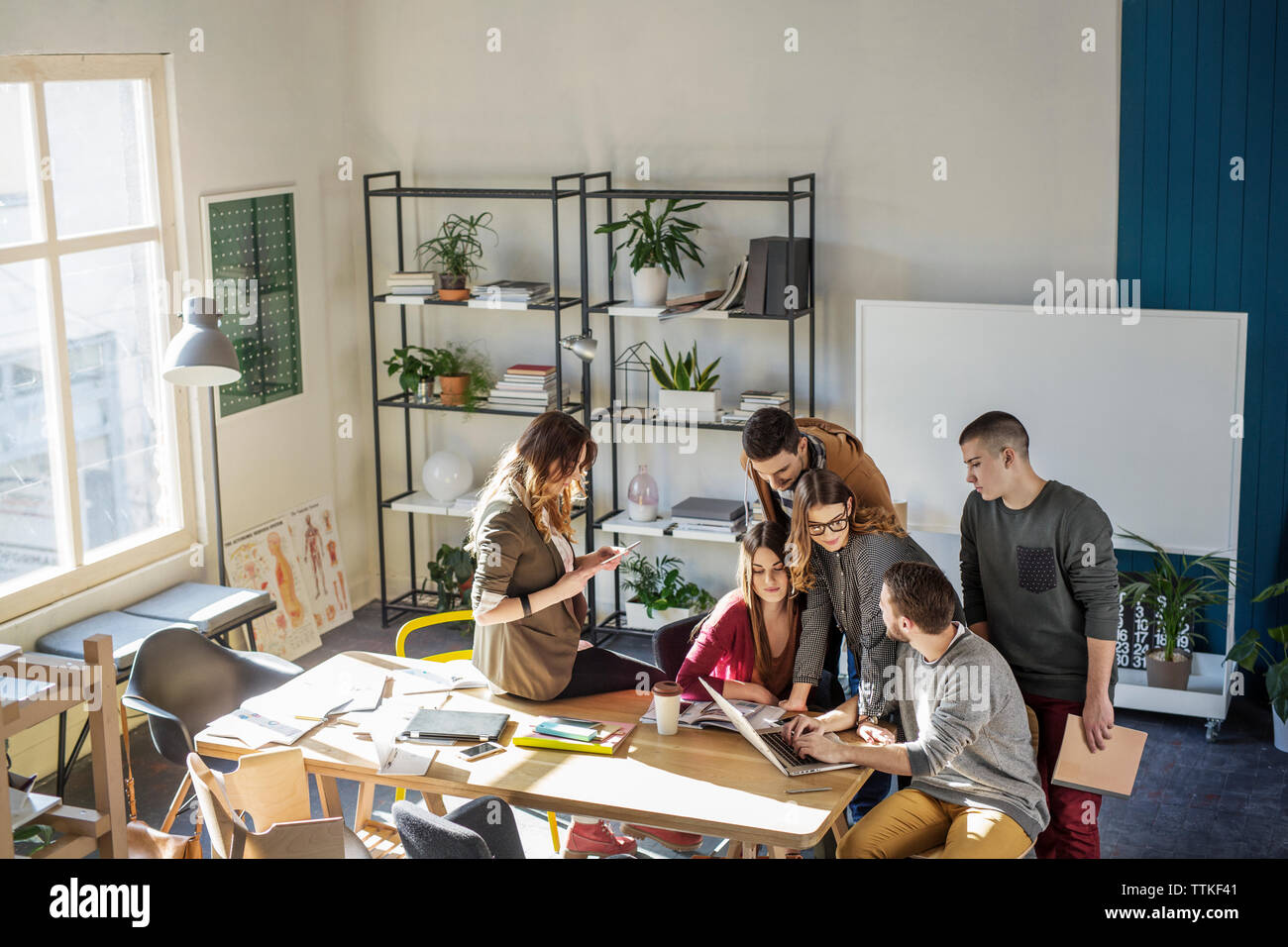 High angle view of students using laptop computer while discussing in ...