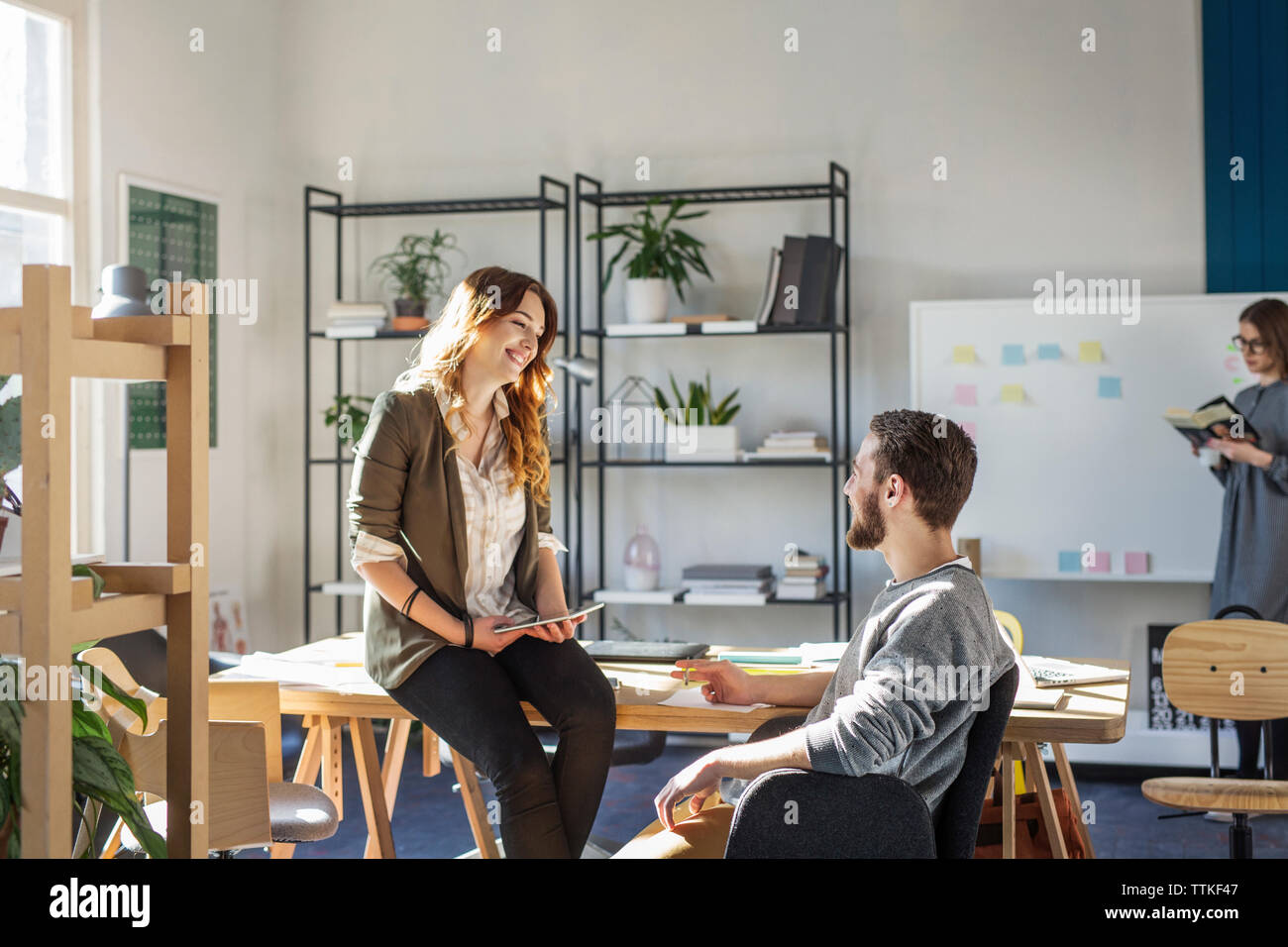 Smiling friends talking while sitting at desk in classroom Stock Photo ...