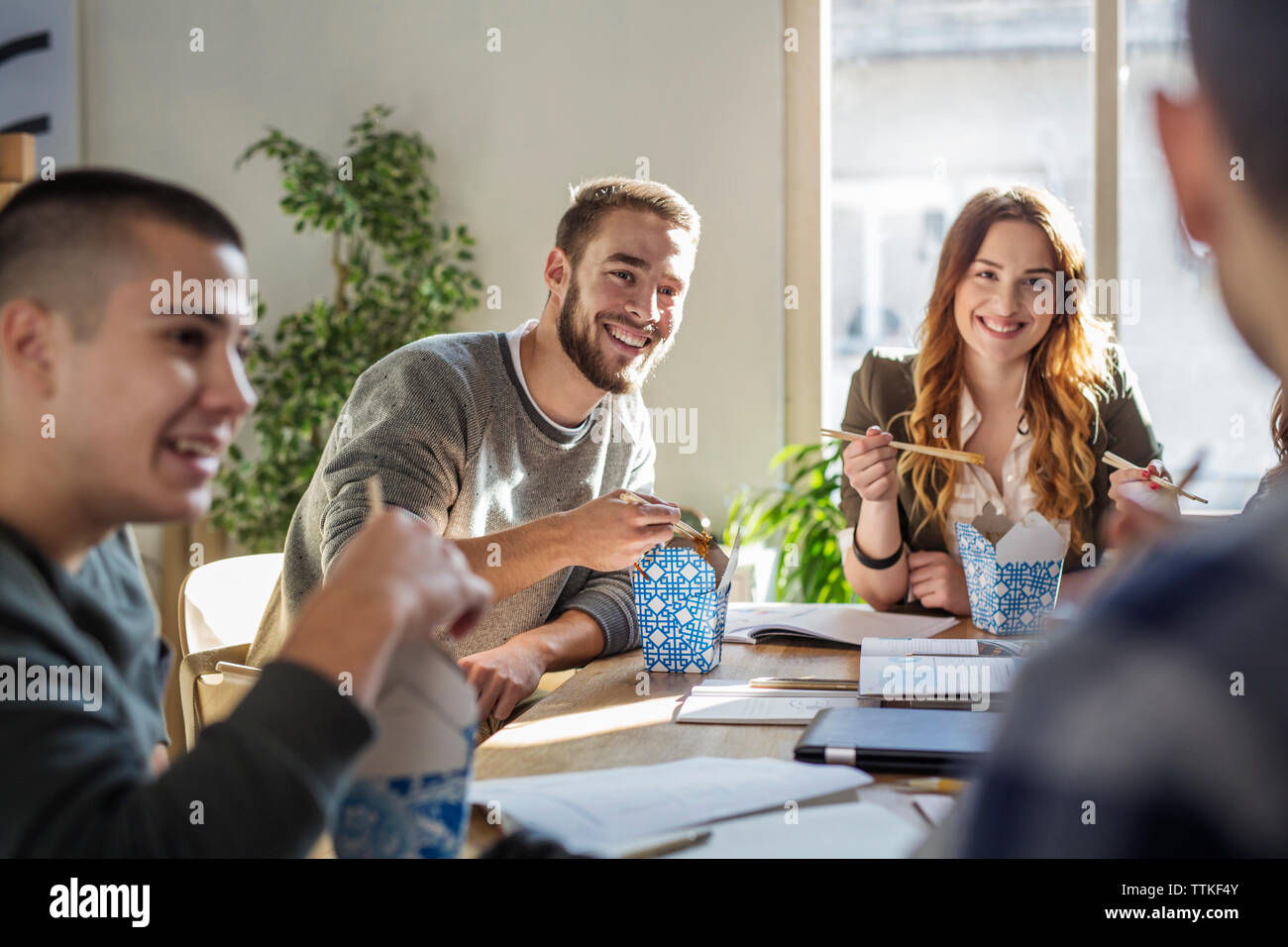 Happy friends having food while sitting at table in classroom Stock ...