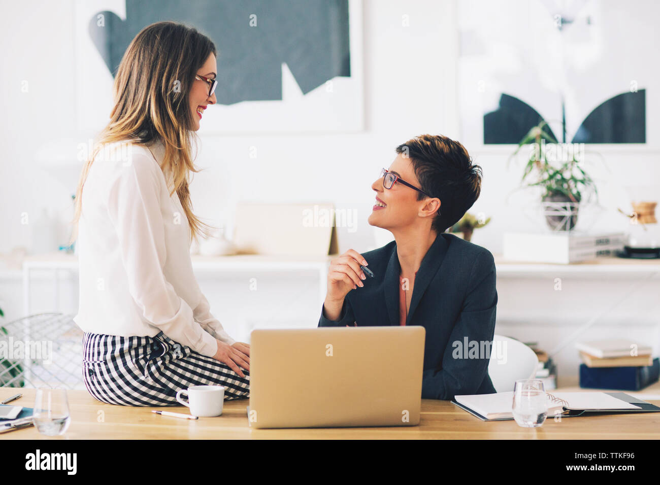 Two colleagues laptop talking office hi-res stock photography and ...