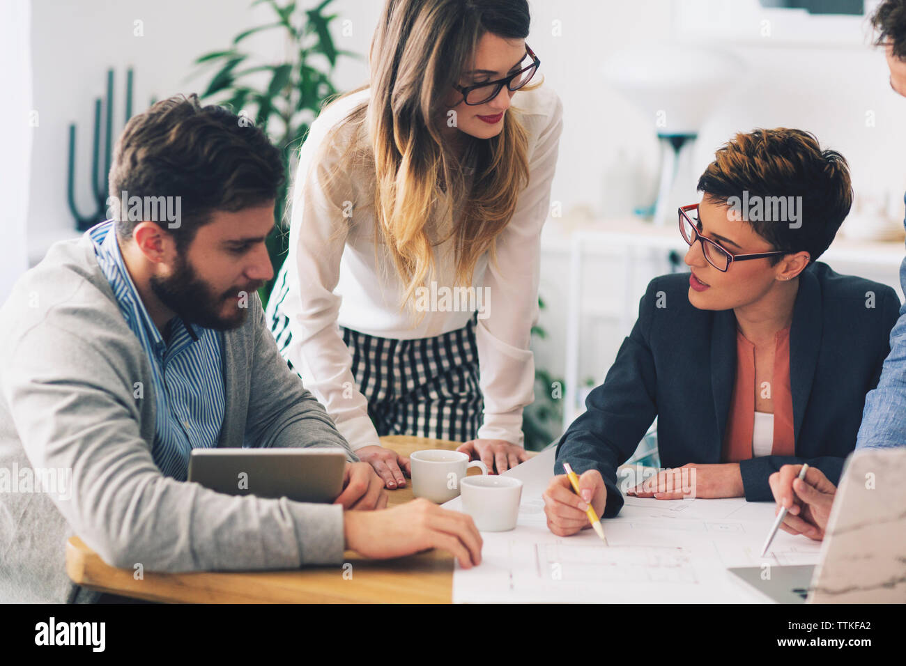 Business people examining blueprints in office Stock Photo - Alamy