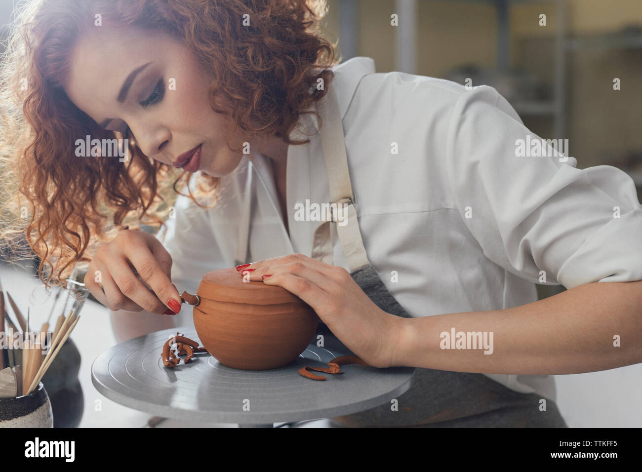 Female potter molding shape to clay with work tool at table Stock Photo ...