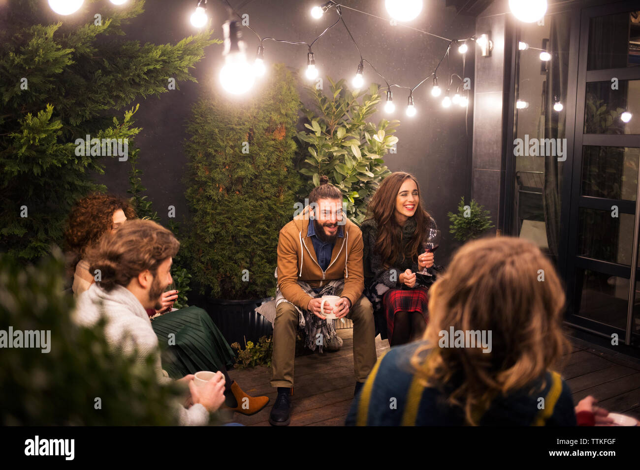 Happy friends talking while enjoying drinks in backyard at night Stock ...