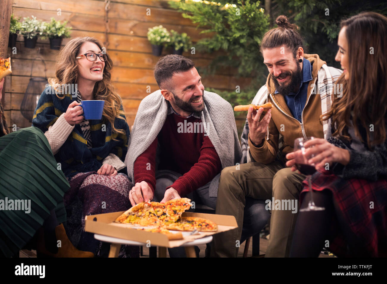 Happy friends having pizza in backyard at night Stock Photo - Alamy