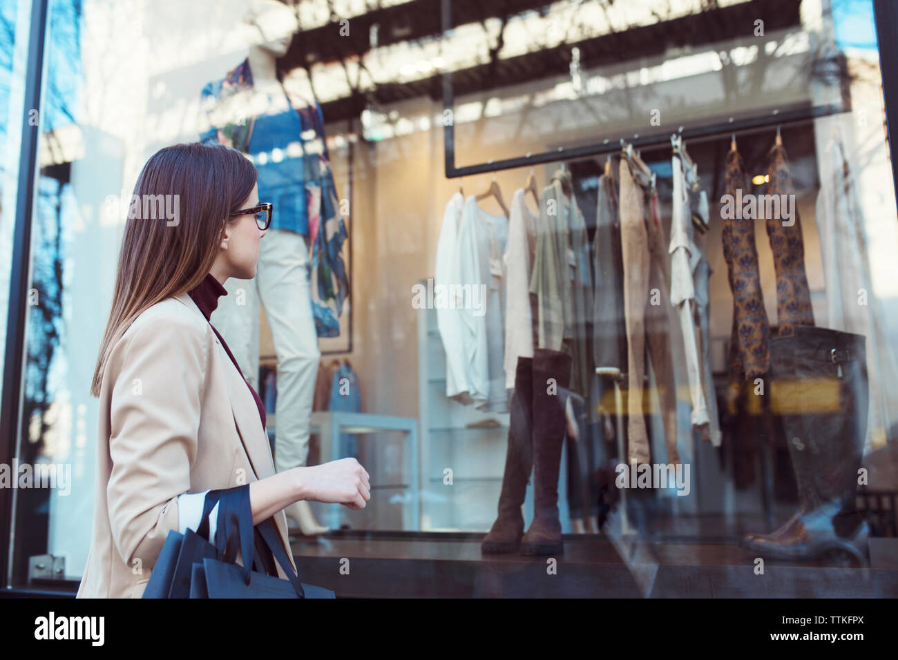 Side view of woman looking in shop window while shopping in city Stock ...