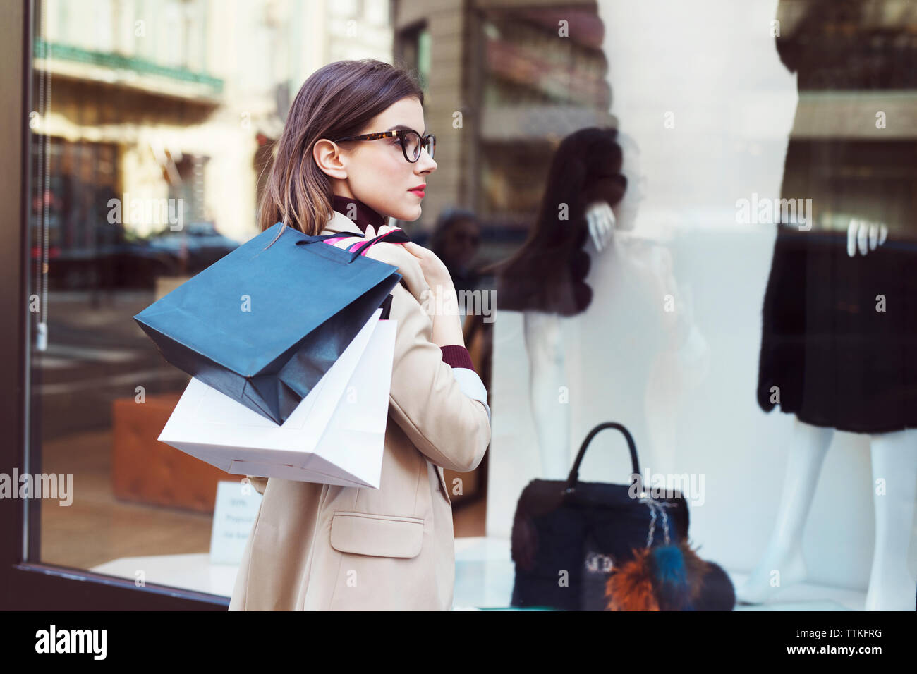 Woman with shopping bags looking in shop window Stock Photo - Alamy