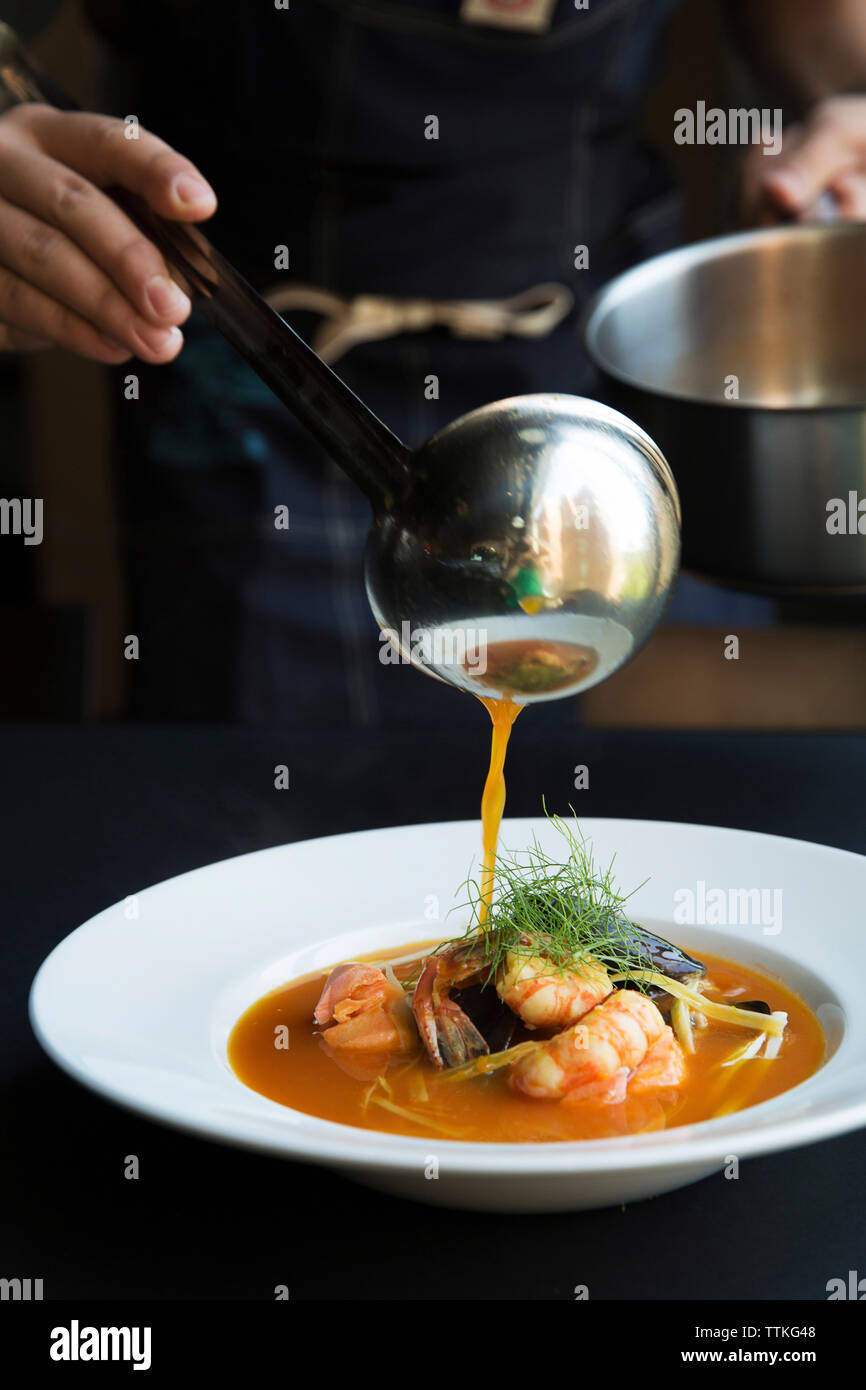 Midsection of chef pouring soup in bowl Stock Photo - Alamy