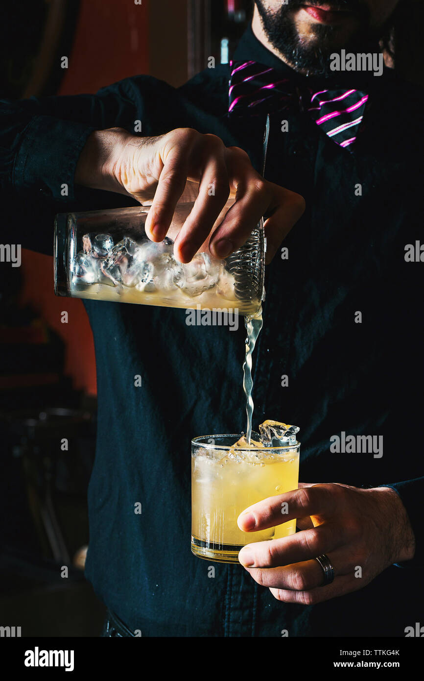 Midsection of bartender preparing drink while standing in bar Stock ...