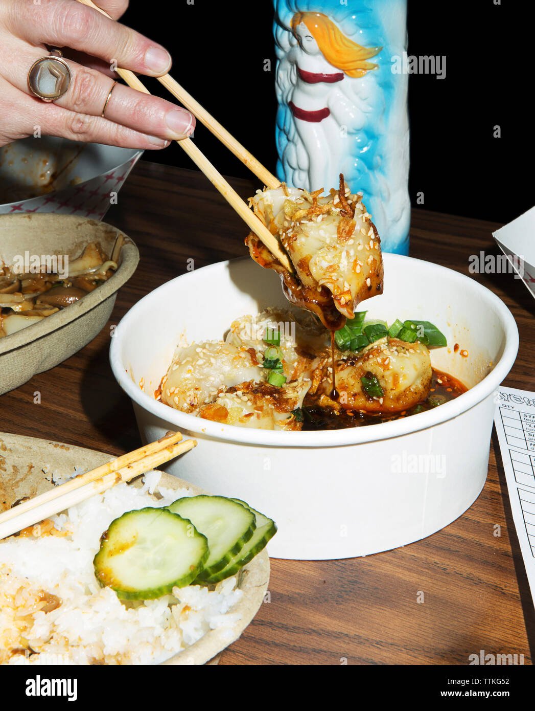 Copped hand holding food with chopsticks at table in restaurant Stock ...