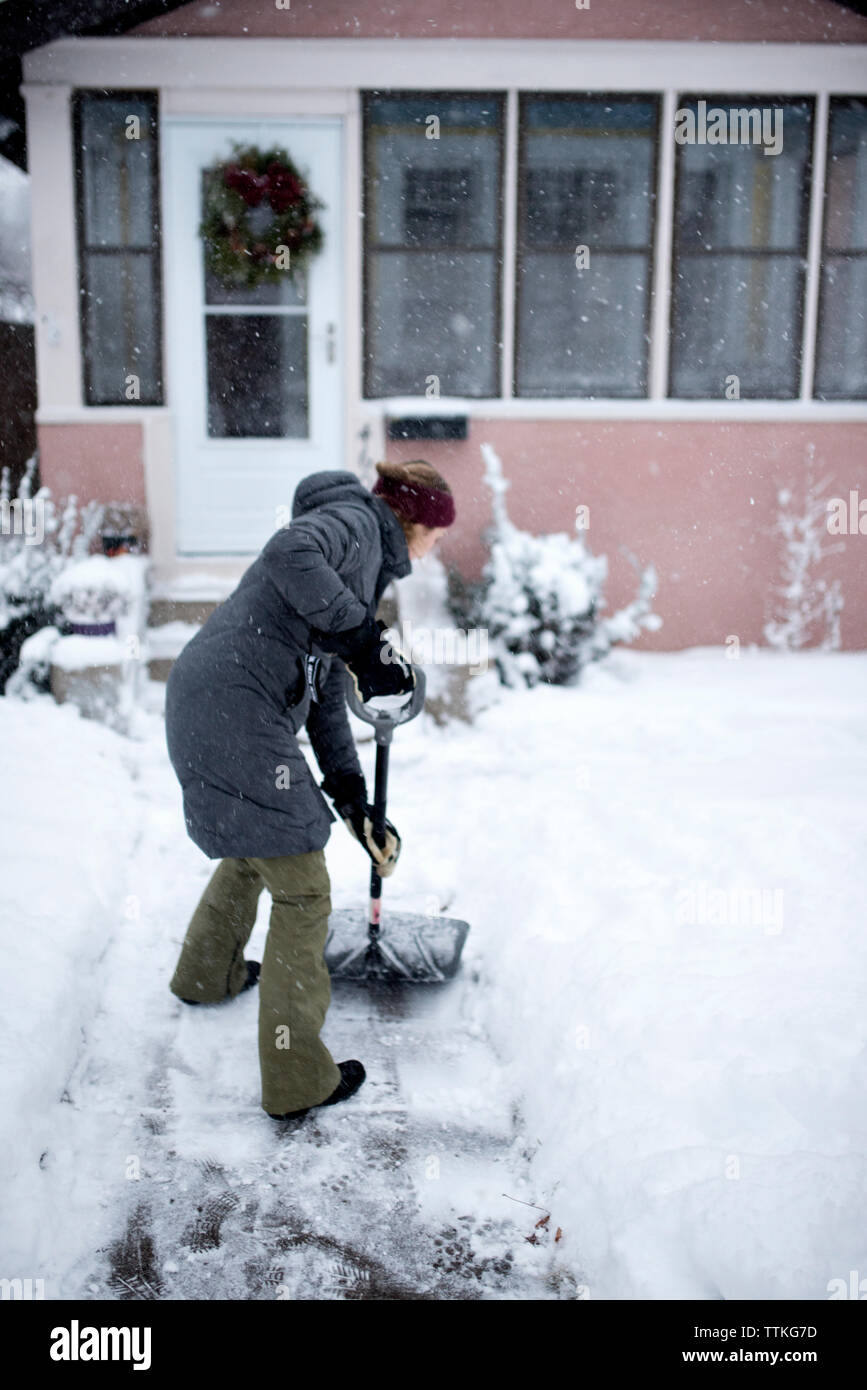 Woman shoveling snow outside house Stock Photo - Alamy