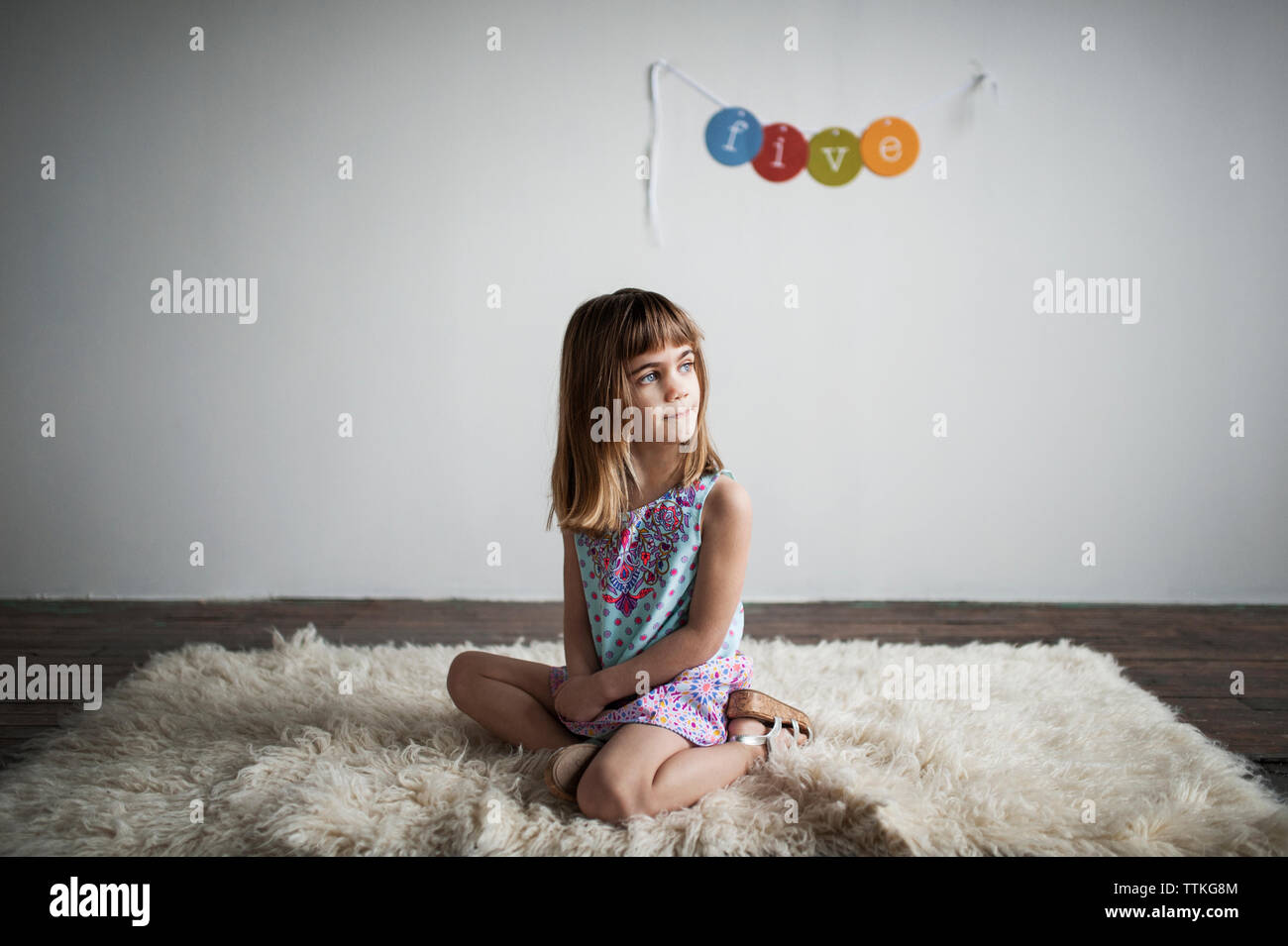 Thoughtful girl sitting on rug at home Stock Photo - Alamy
