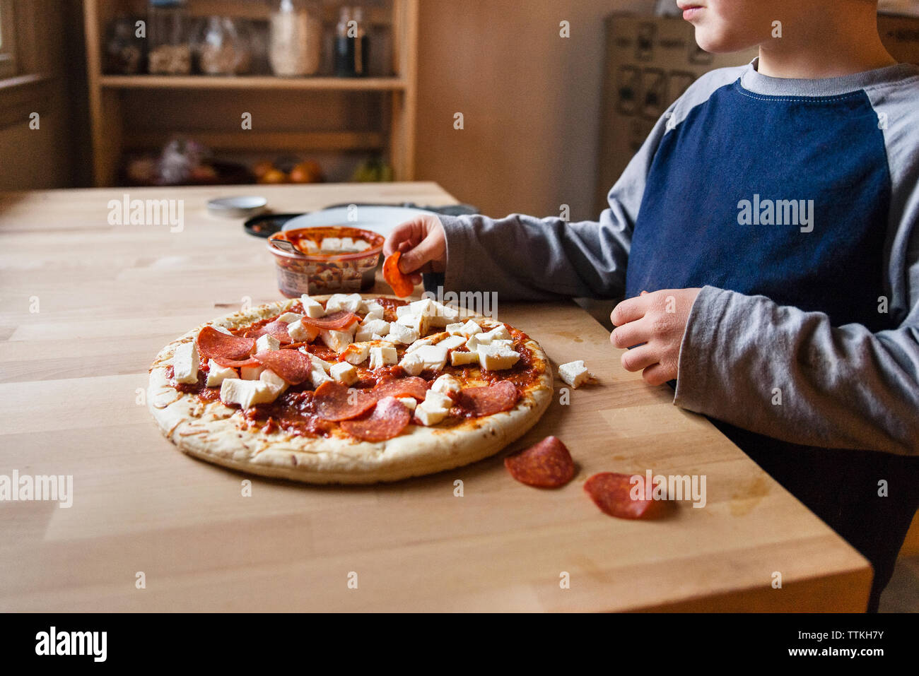 Midsection of boy preparing pizza at home Stock Photo - Alamy