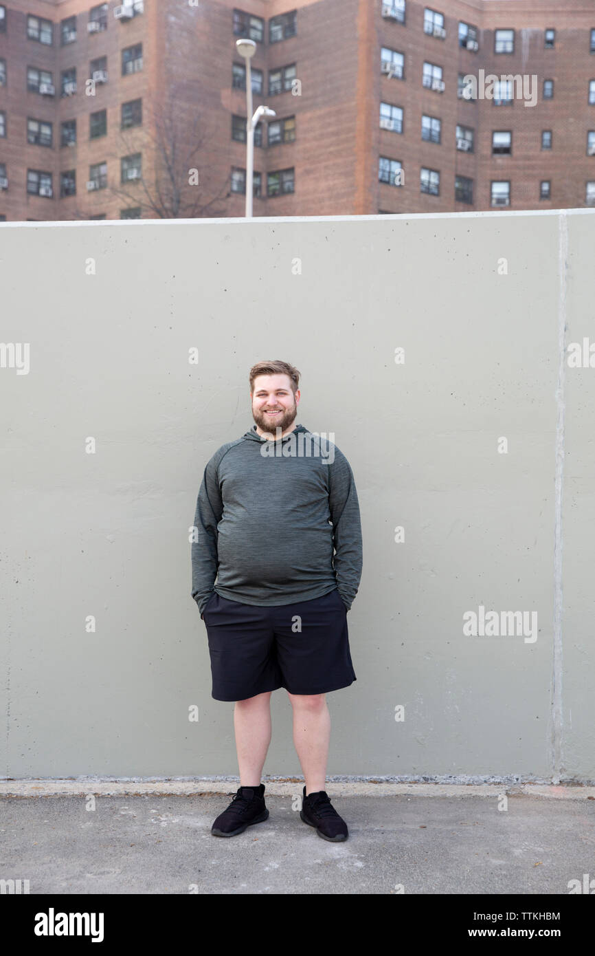 Full length portrait of overweight man with hands in pockets standing ...