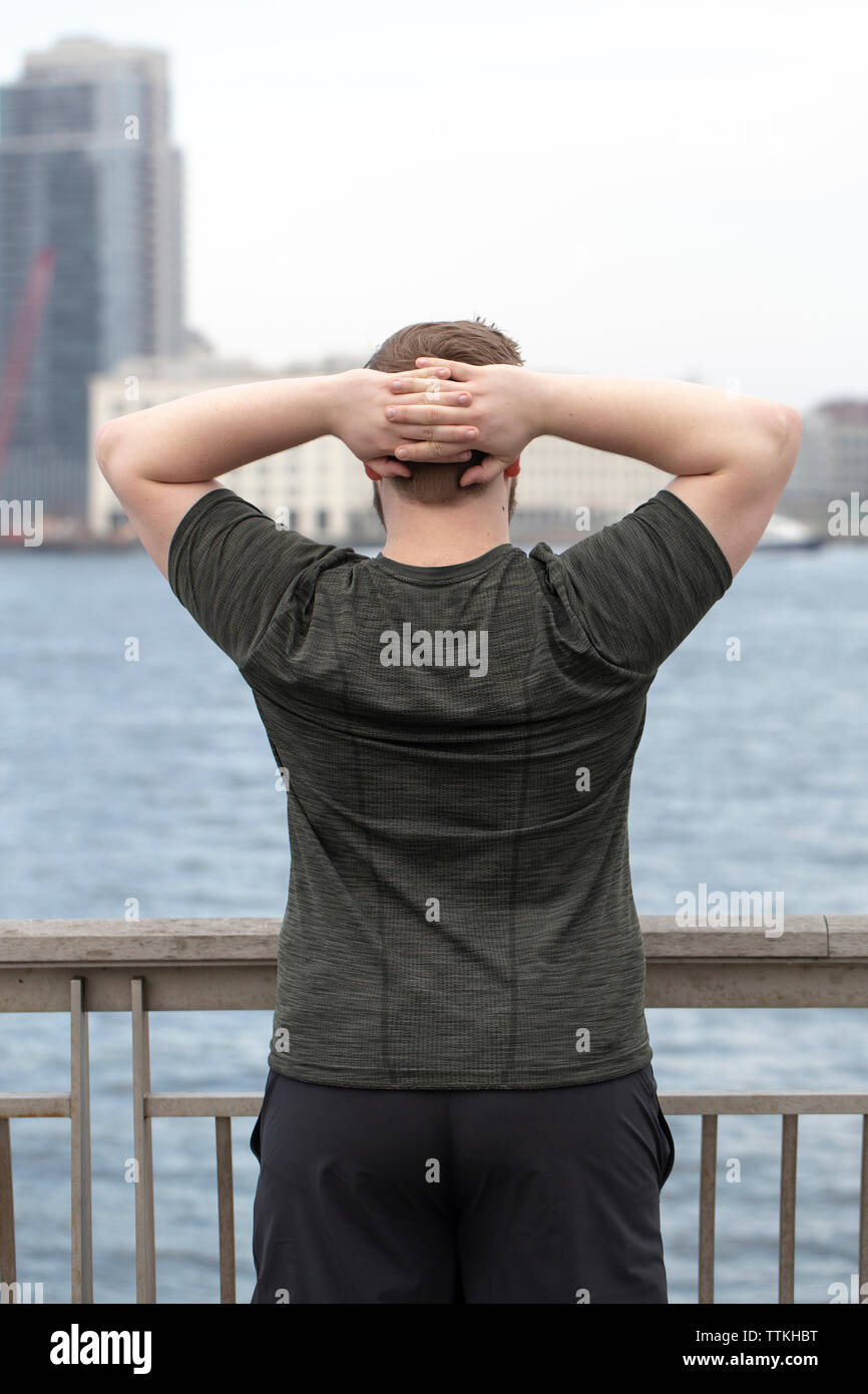 Rear view of overweight man with hands behind head exercising on bridge ...