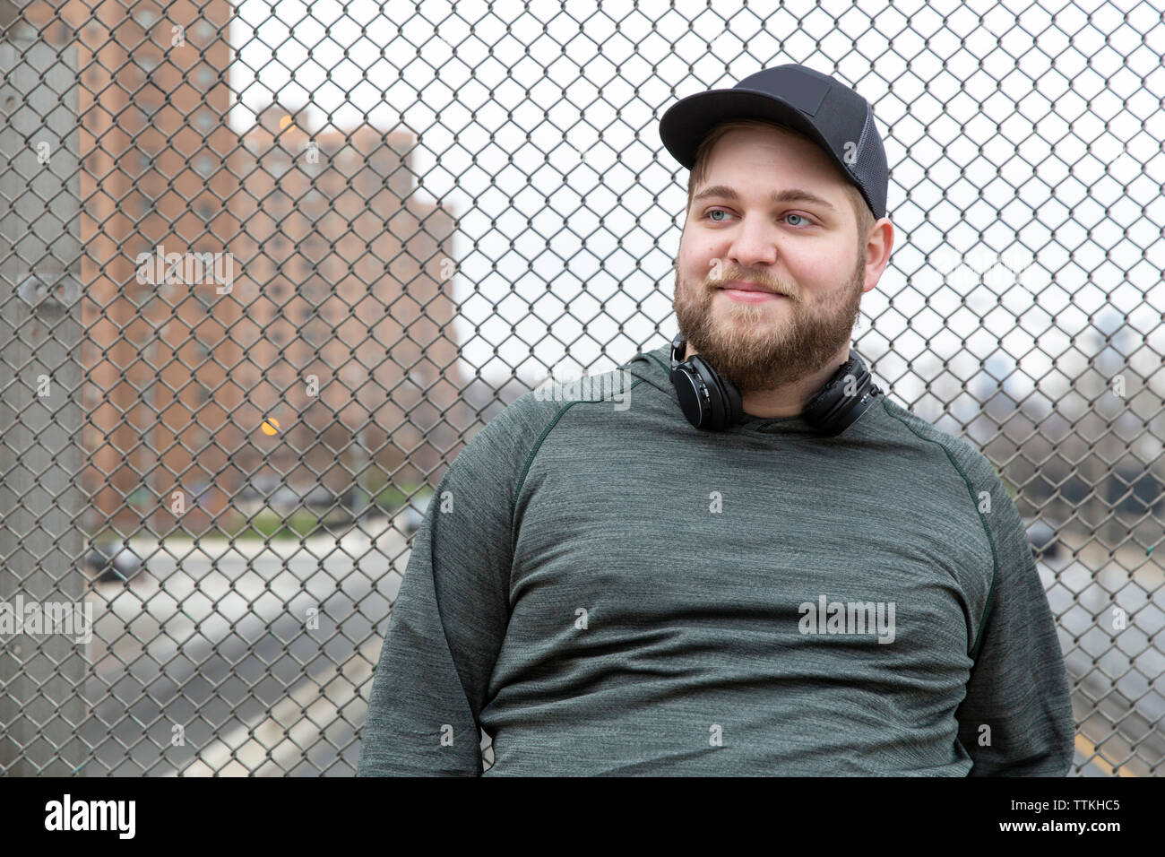 Smiling overweight man with headphones looking away while standing ...