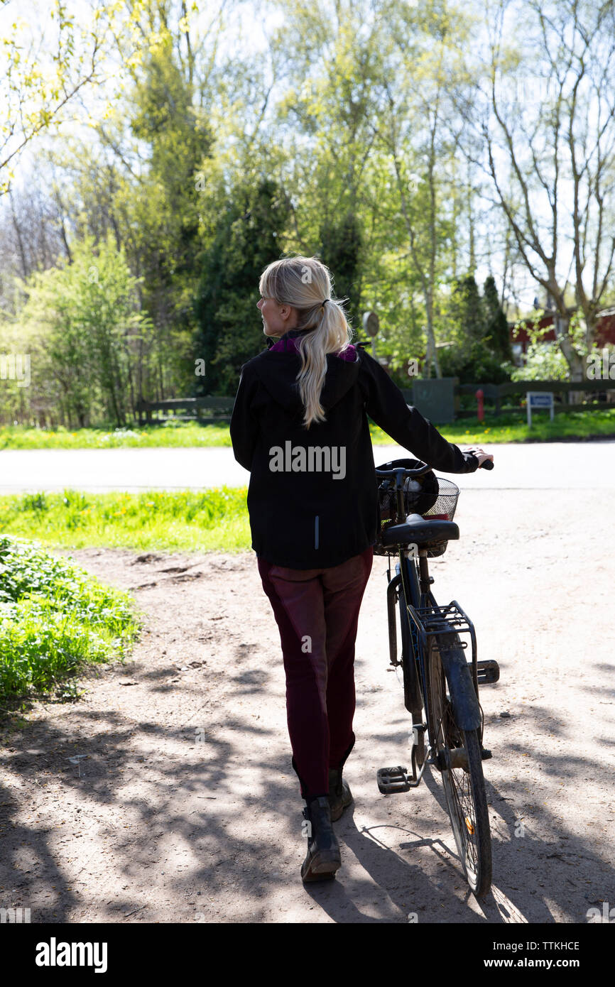Rear view of woman with bicycle walking at farm Stock Photo - Alamy