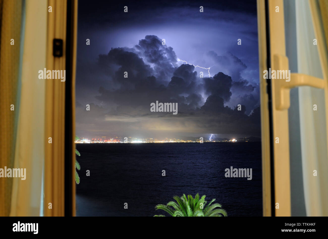 View of storm clouds over sea seen through window at night Stock Photo ...
