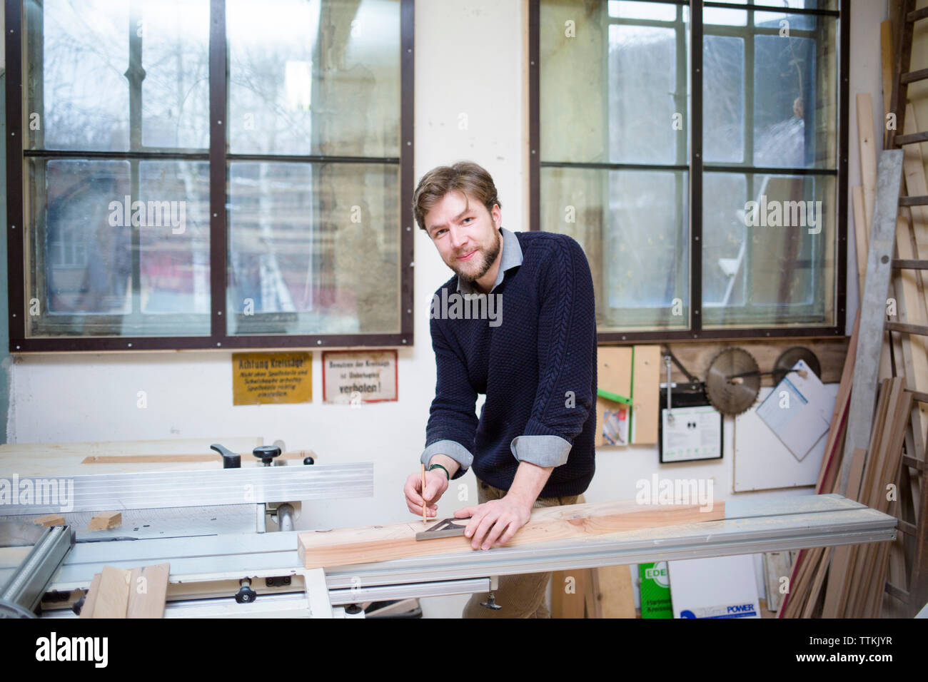 Portrait of carpenter measuring wooden planks at workshop Stock Photo ...