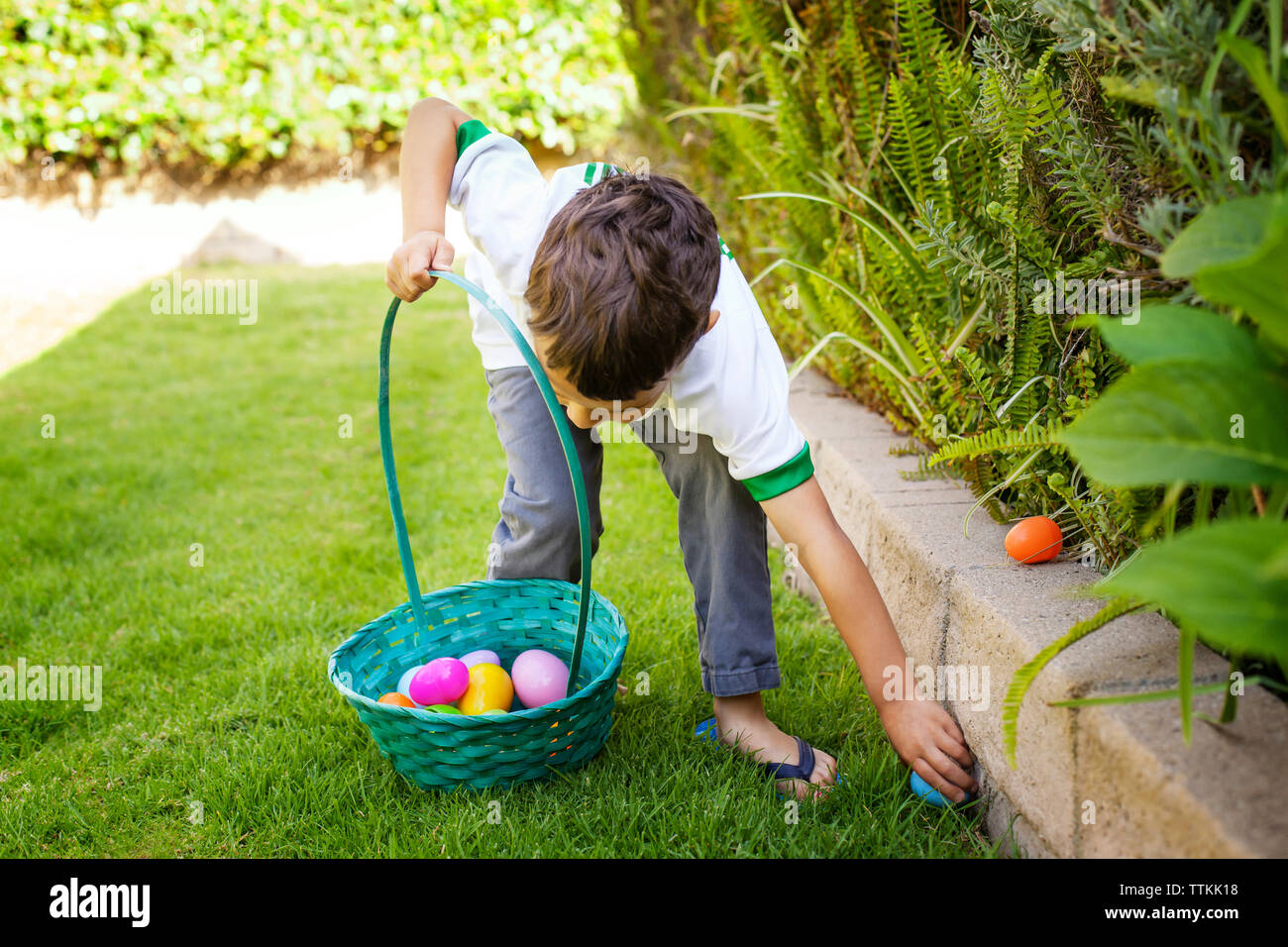 Boy collecting toys on grassy field Stock Photo - Alamy