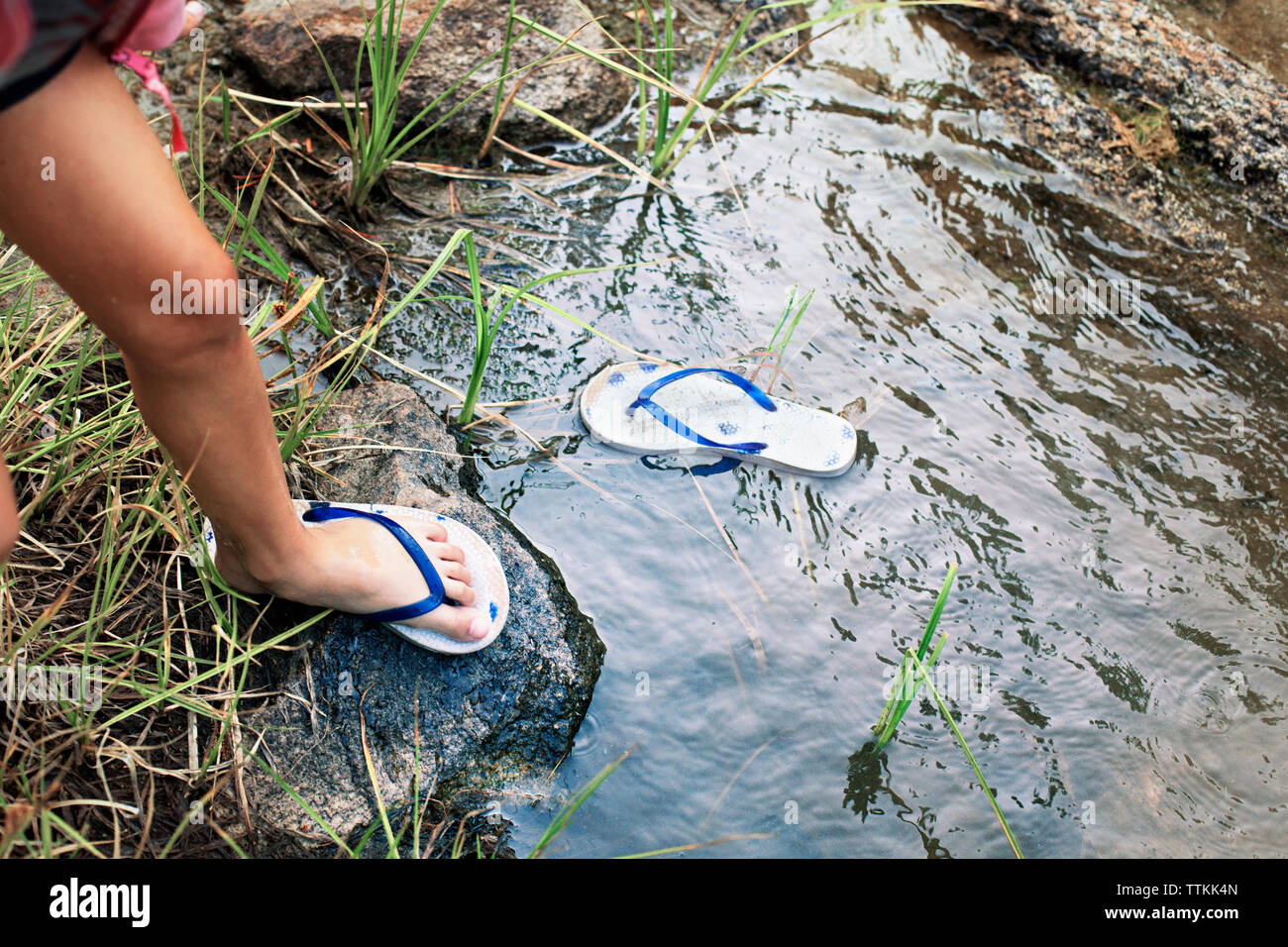Low section of girl standing on rock by stream Stock Photo - Alamy