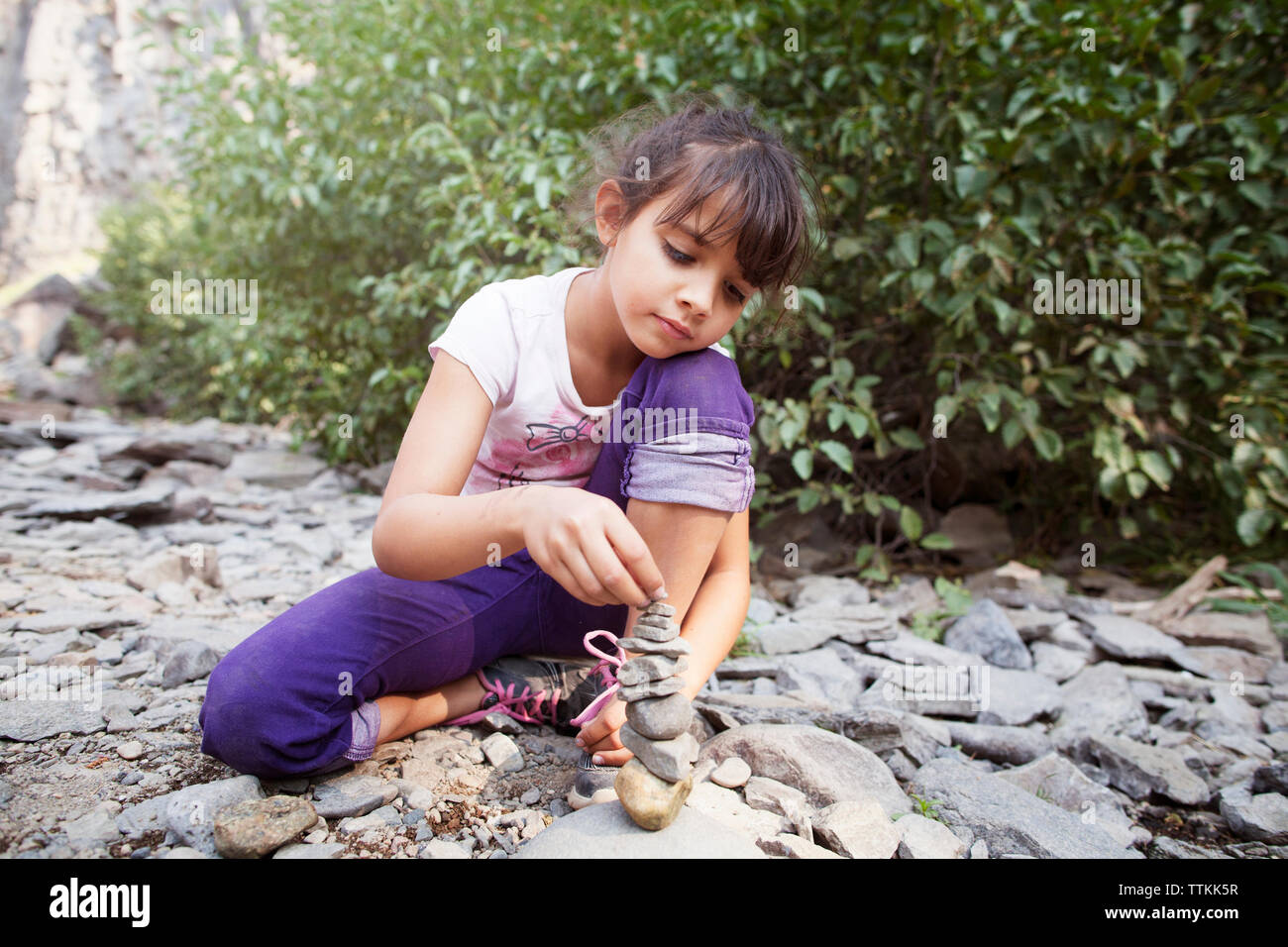 Girl making stone stack on field against plants Stock Photo - Alamy