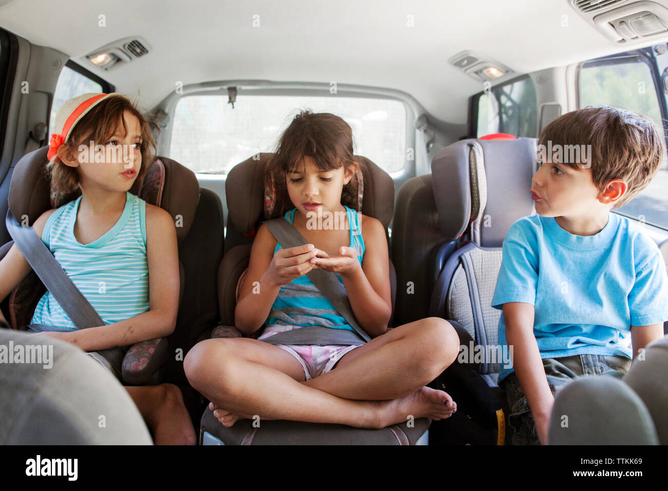 Front view of siblings sitting in car Stock Photo - Alamy