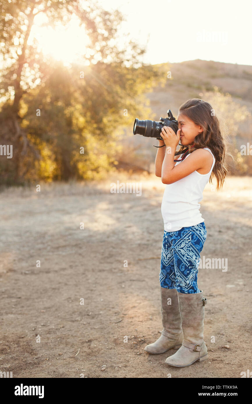 Side view of girl standing on field and photographing with camera Stock ...