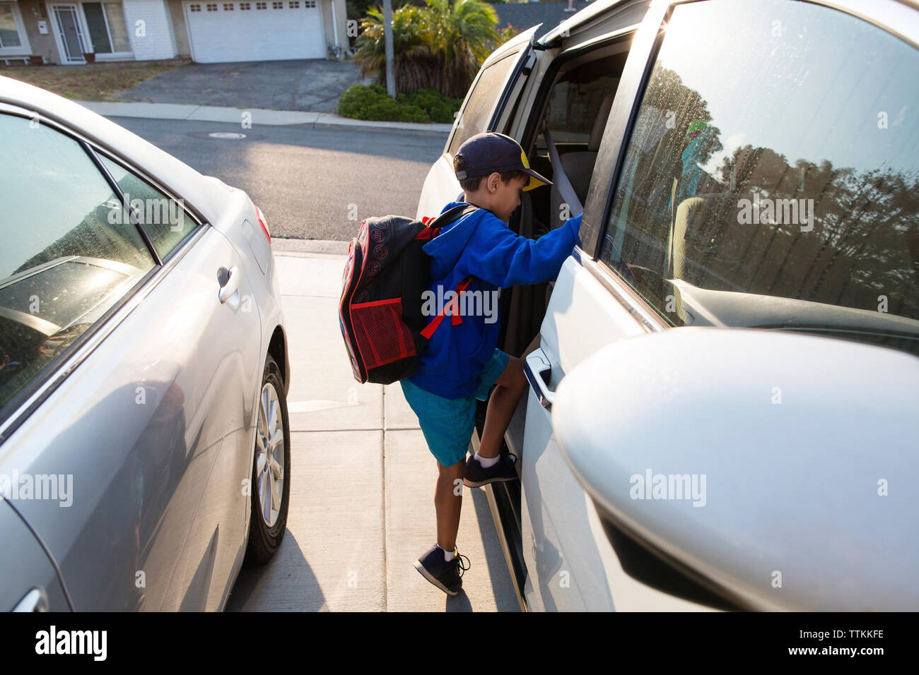 Boy with backpack entering car Stock Photo - Alamy