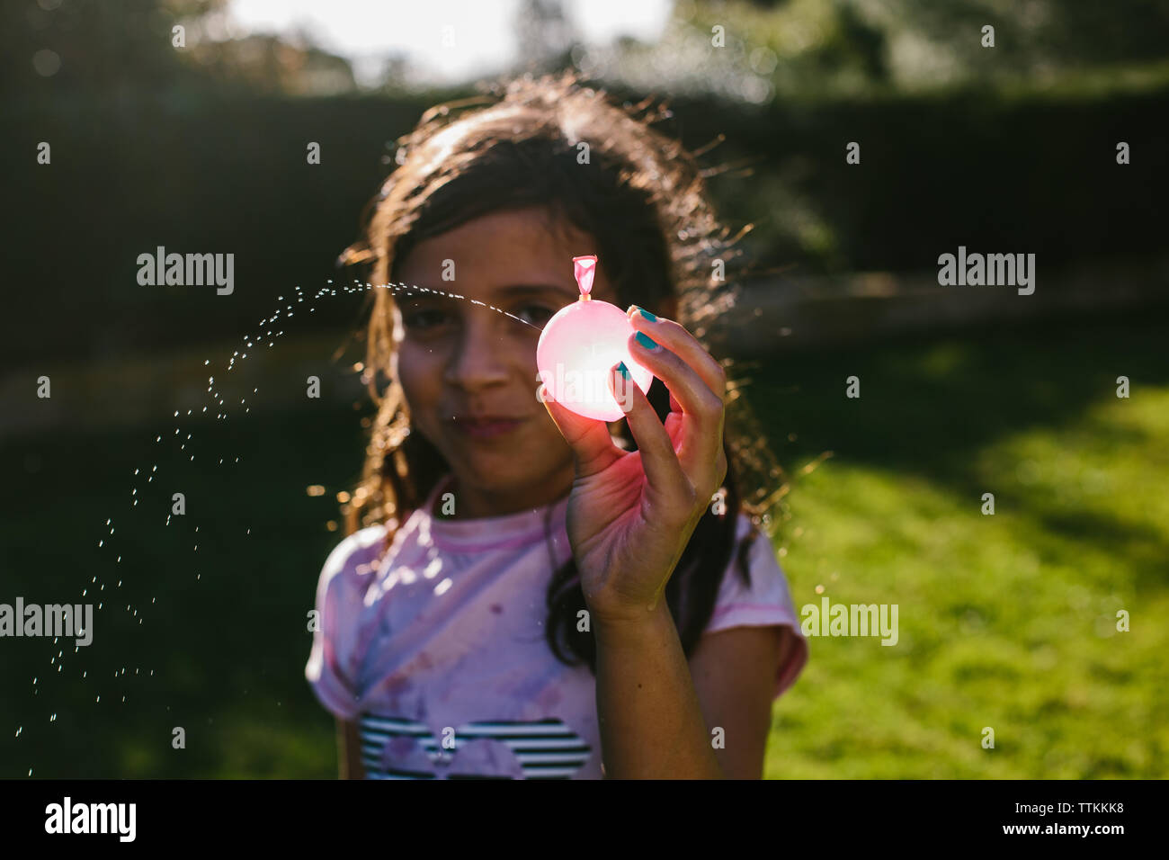 Portrait of girl spraying from water bomb at backyard Stock Photo - Alamy