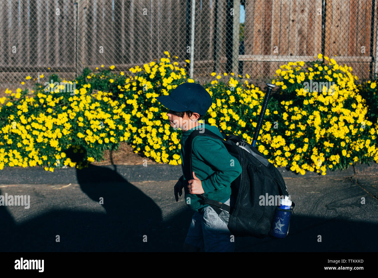 Side view of boy carrying backpack while walking on footpath Stock ...