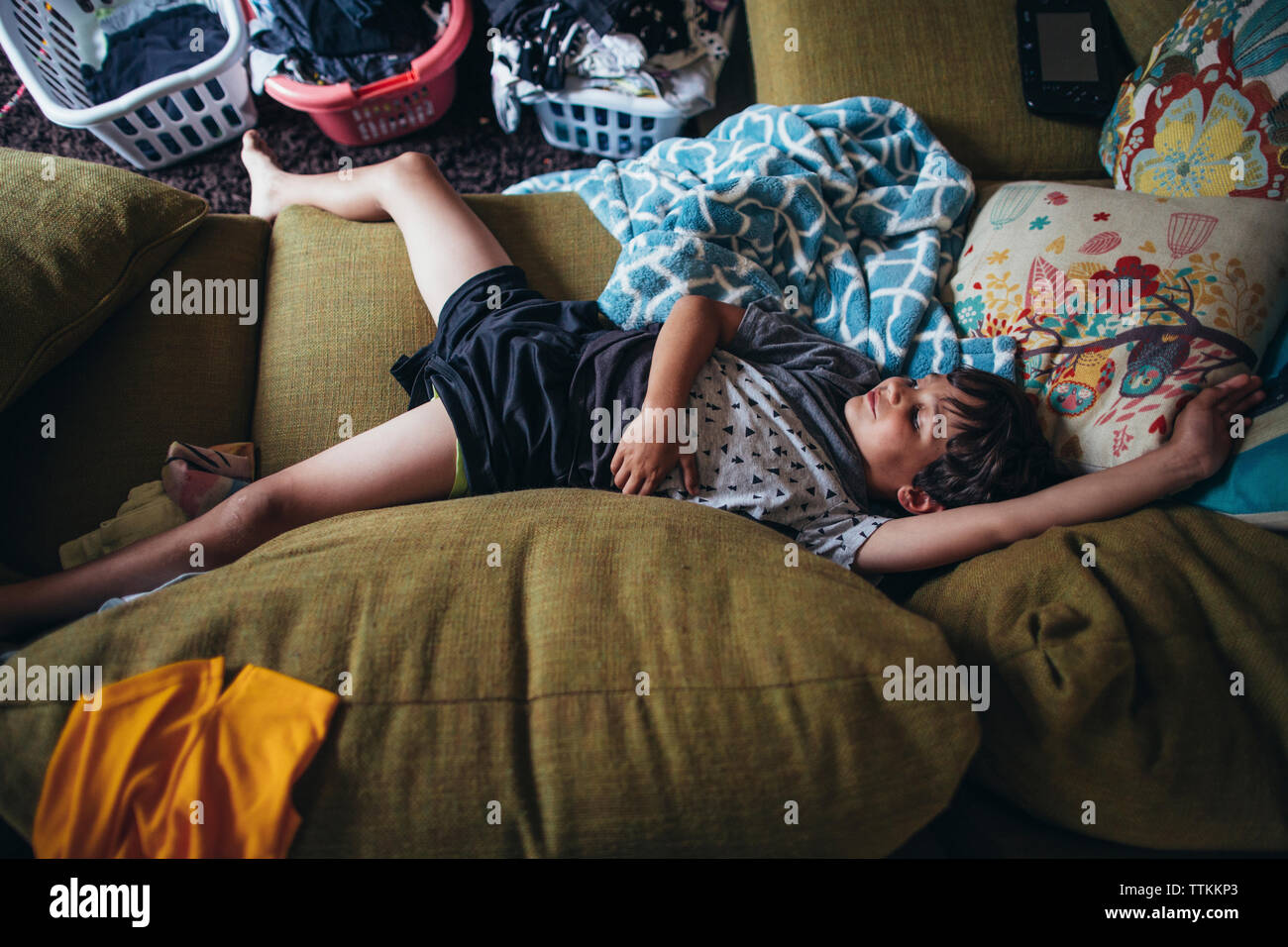 Overhead view of boy sleeping on messy sofa at home Stock Photo - Alamy