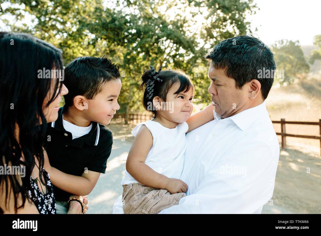 Happy parents and son looking at cute daughter making face against ...