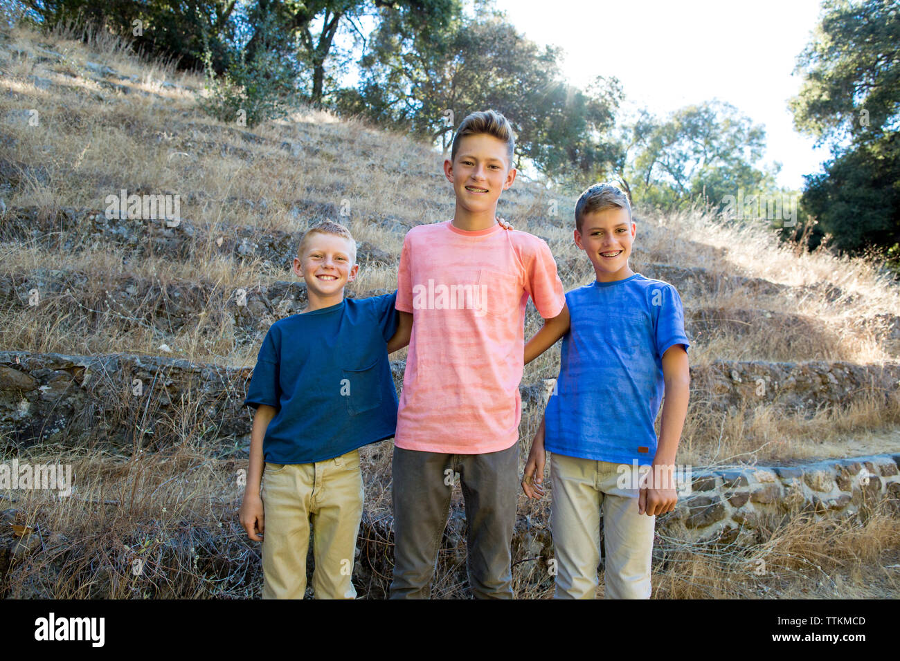 Three brothers smile for camera in an outside portrait Stock Photo - Alamy