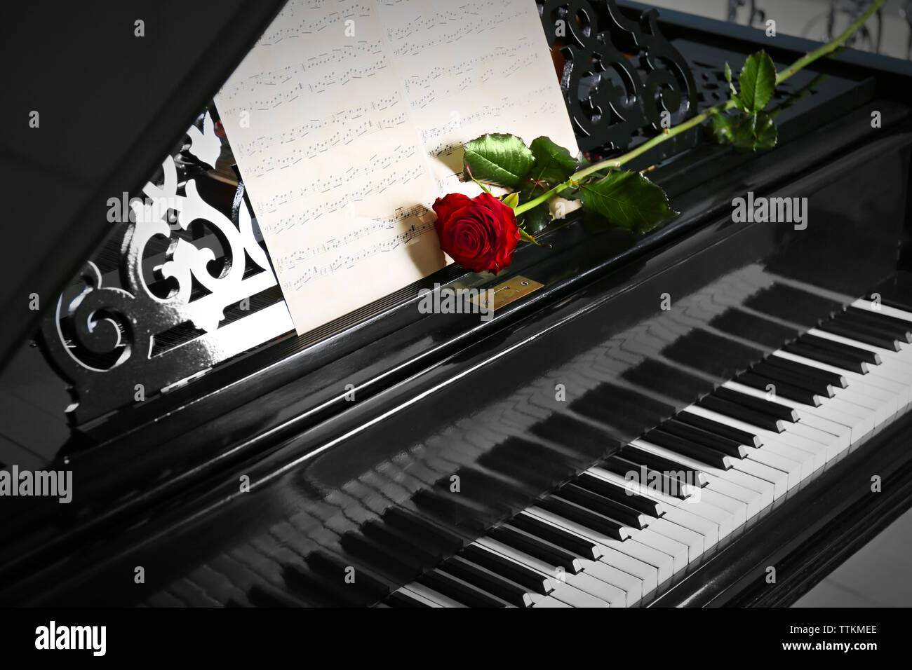 Musical notes and red rose on black piano, close up Stock Photo - Alamy