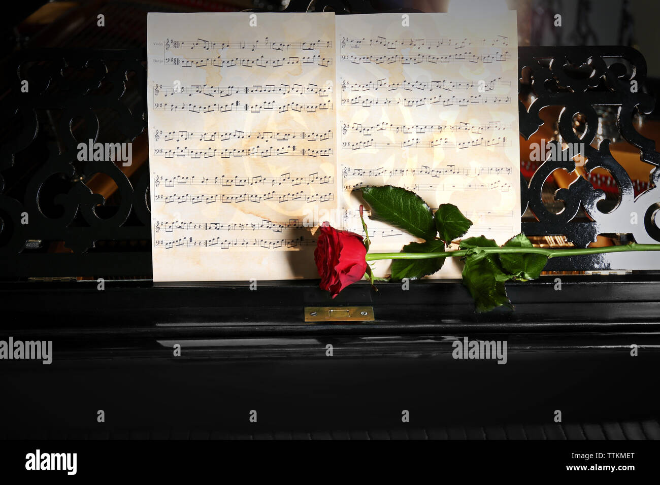 Musical notes and red rose on black piano, close up Stock Photo - Alamy