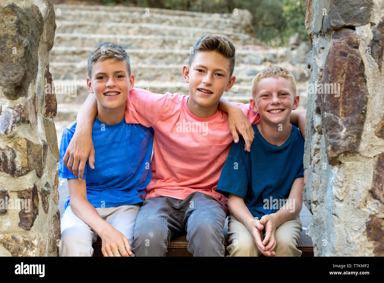 Three brothers sit together for a portrait by a stone wall Stock Photo ...