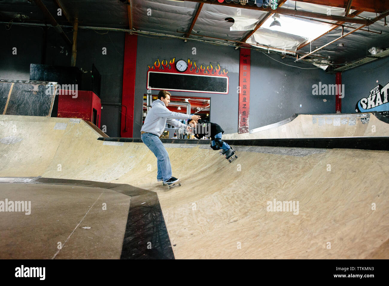 Skateboarding instructor holds student's hands while carving Stock ...