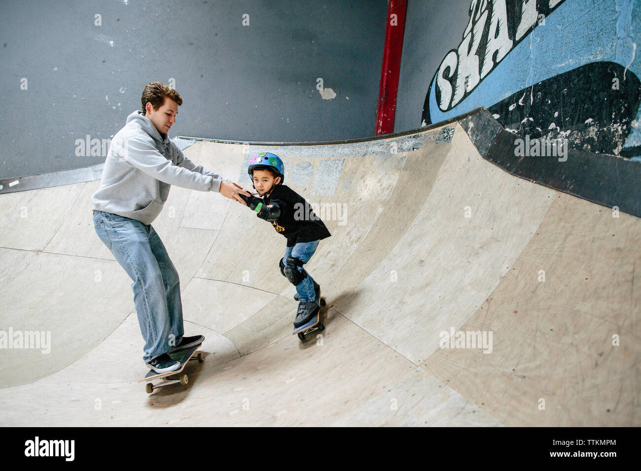 Little boy holds hands with skateboard instructor while carving Stock ...