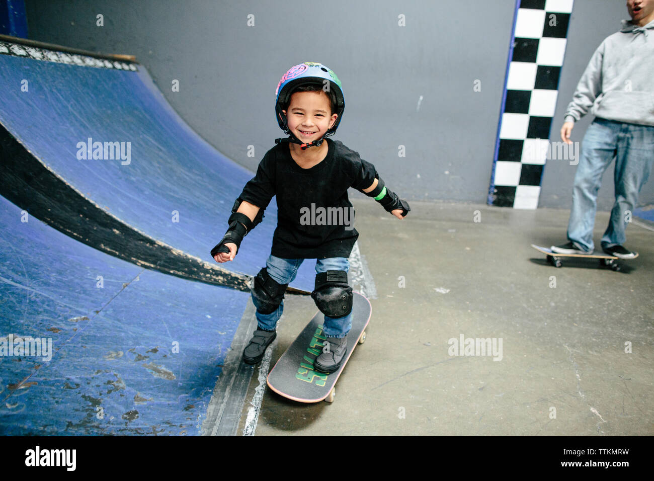 Little boy smiles big while riding his instructor's skateboard Stock ...