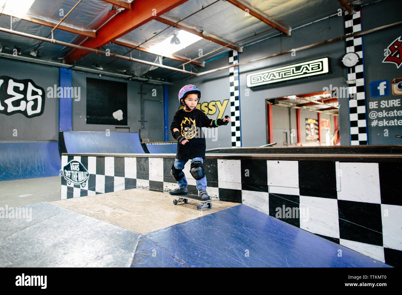A boy begins to skateboard down a ramp in an indoor skatepark Stock ...